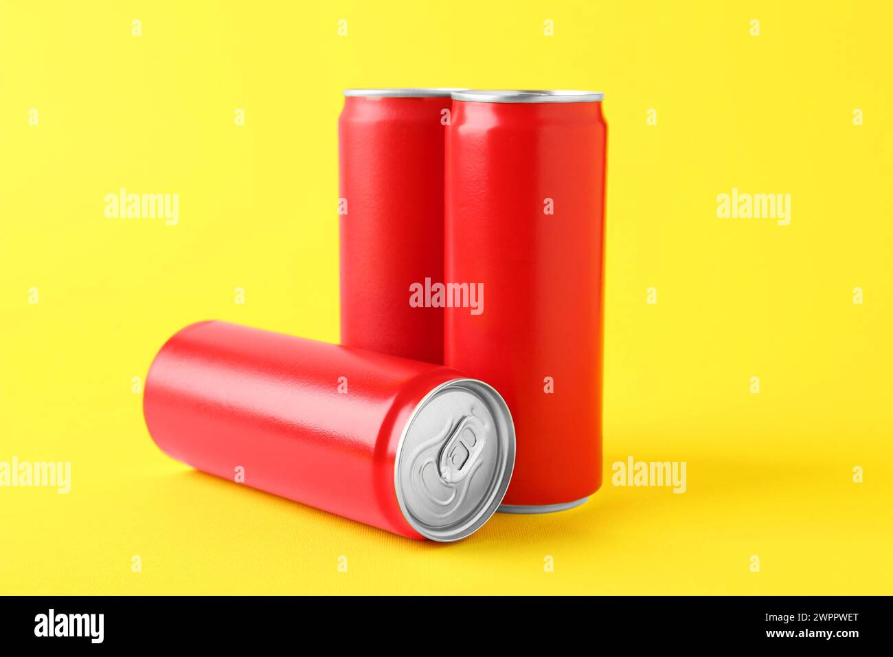 Energy drinks in red cans on yellow background Stock Photo - Alamy