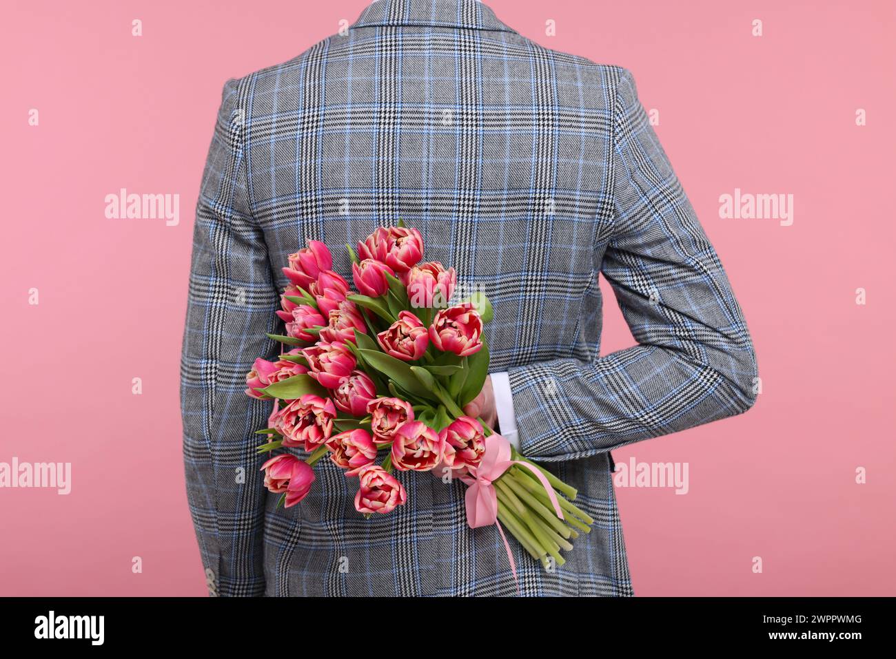 Man hiding beautiful bouquet on pink background, back view Stock Photo ...