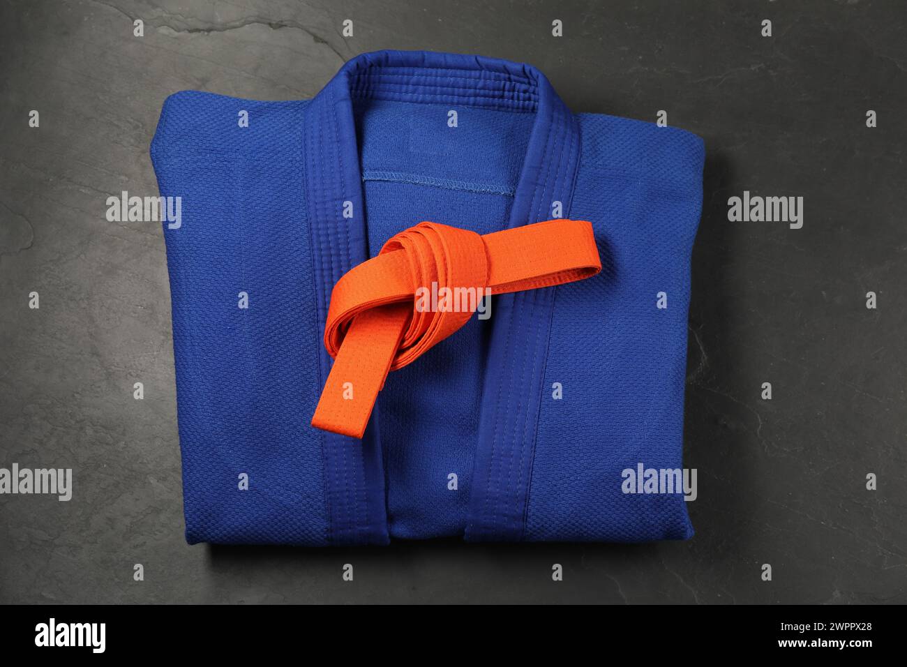 Orange karate belt and blue kimono on gray background, top view Stock ...
