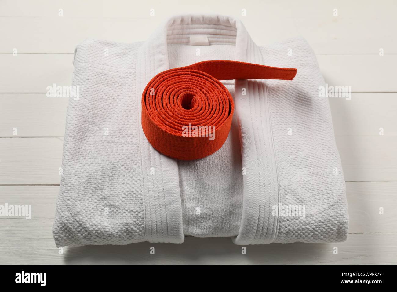 Orange karate belt and white kimono on wooden background Stock Photo ...
