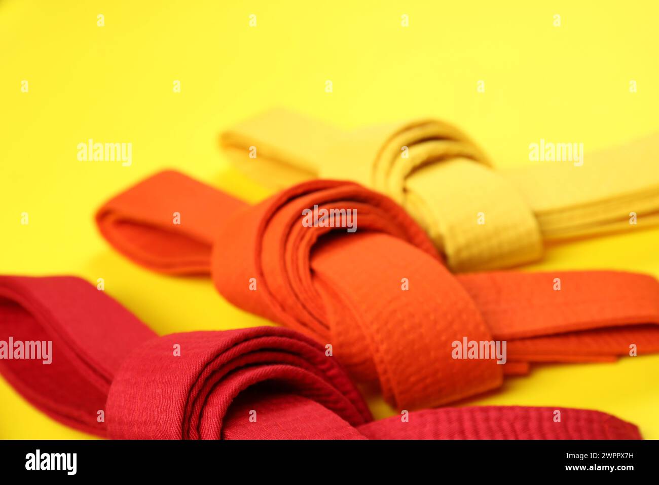 Colorful karate belts on yellow background, closeup Stock Photo - Alamy