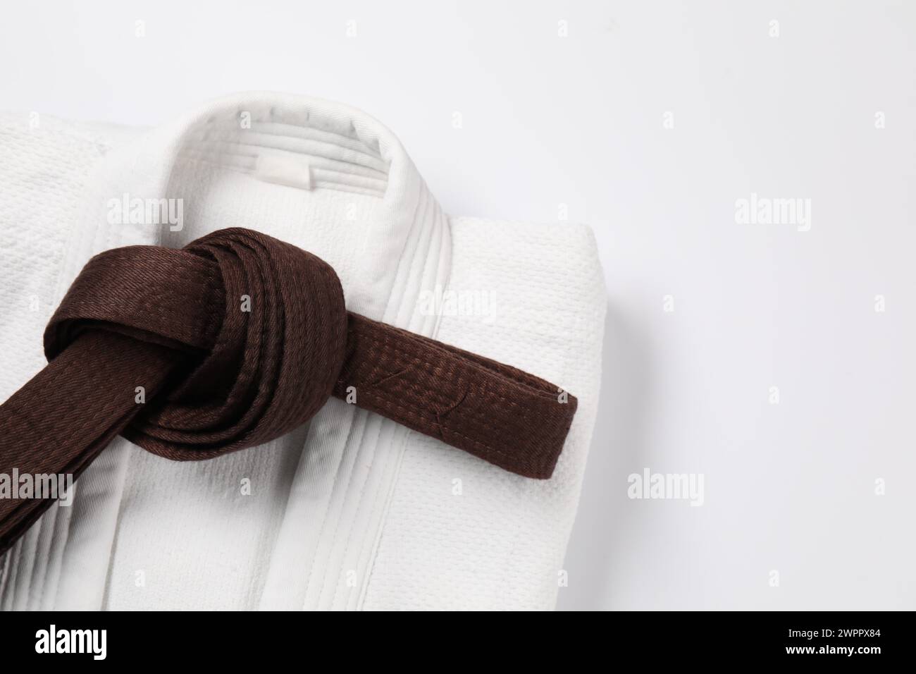 Brown karate belt and kimono on white background, top view. Space for ...