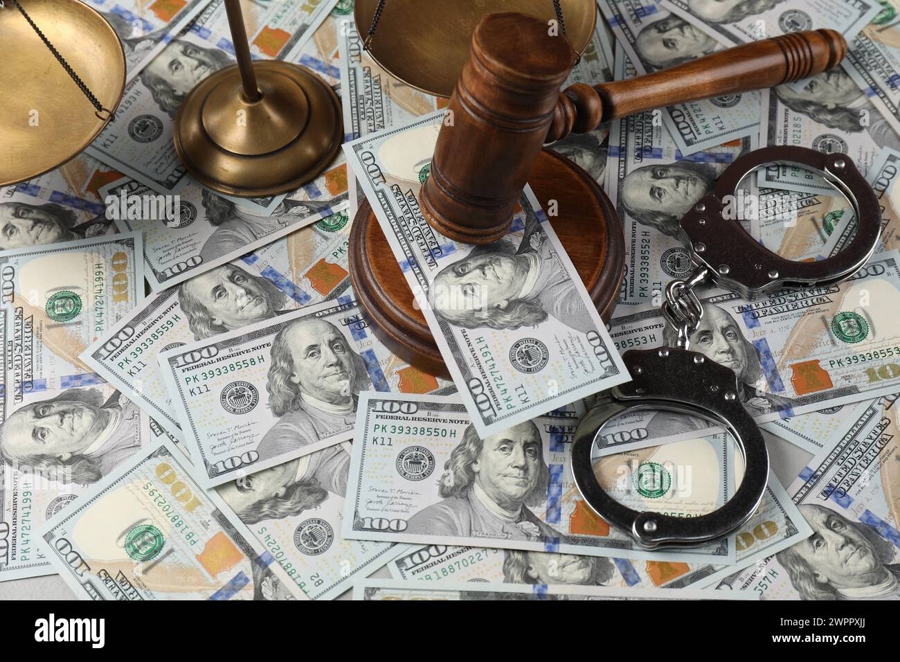 Judge's gavel, handcuffs and scales of justice on dollar banknotes ...