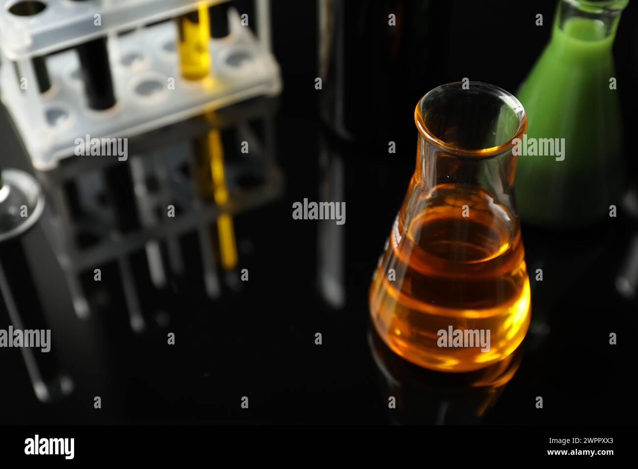 Laboratory glassware with different types of oil on black background ...
