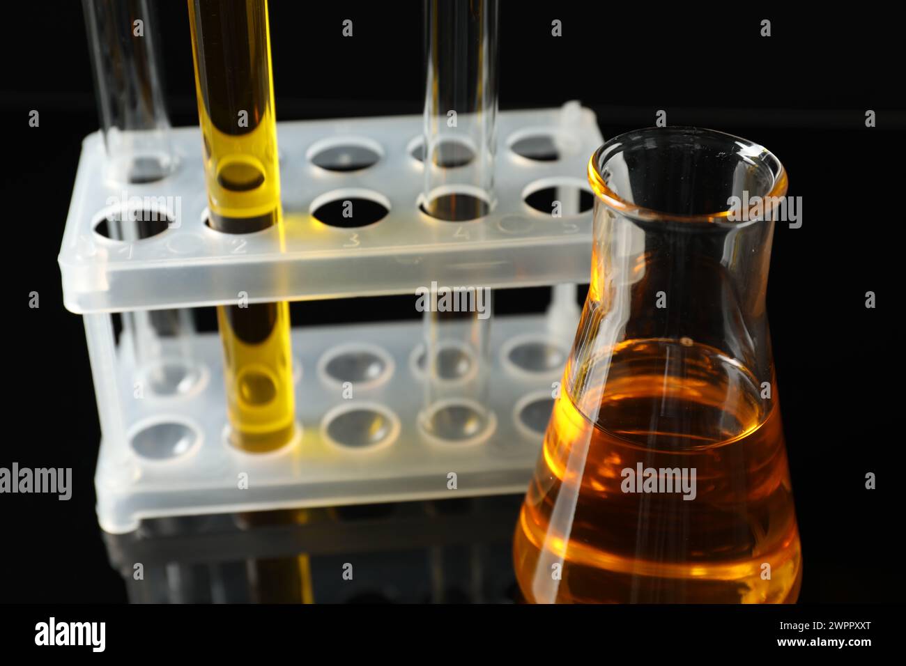 Laboratory glassware with different types of oil on black background ...