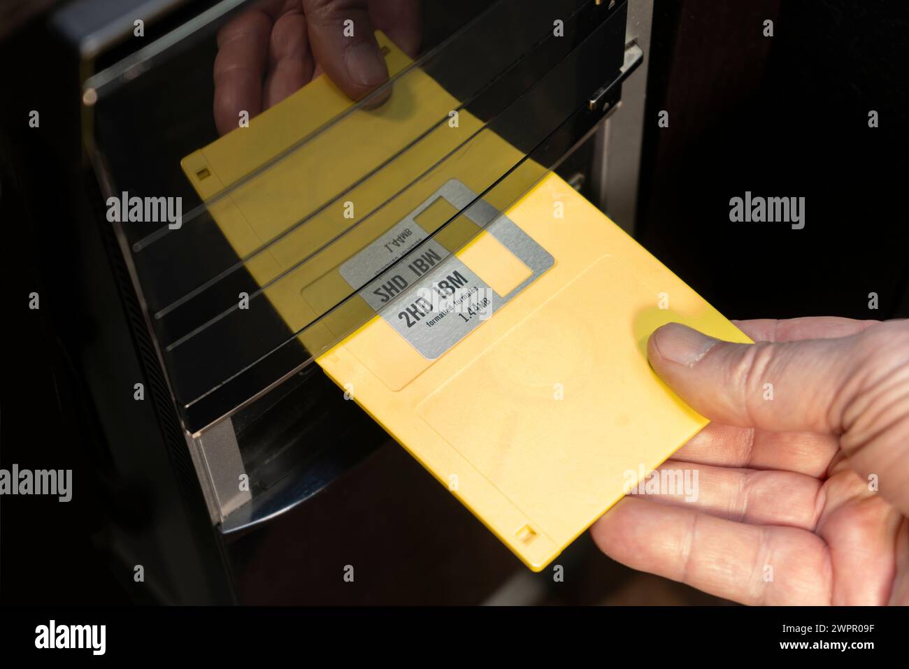 Inserting an old 3 and a half inch floppy disk into a desktop computer ...