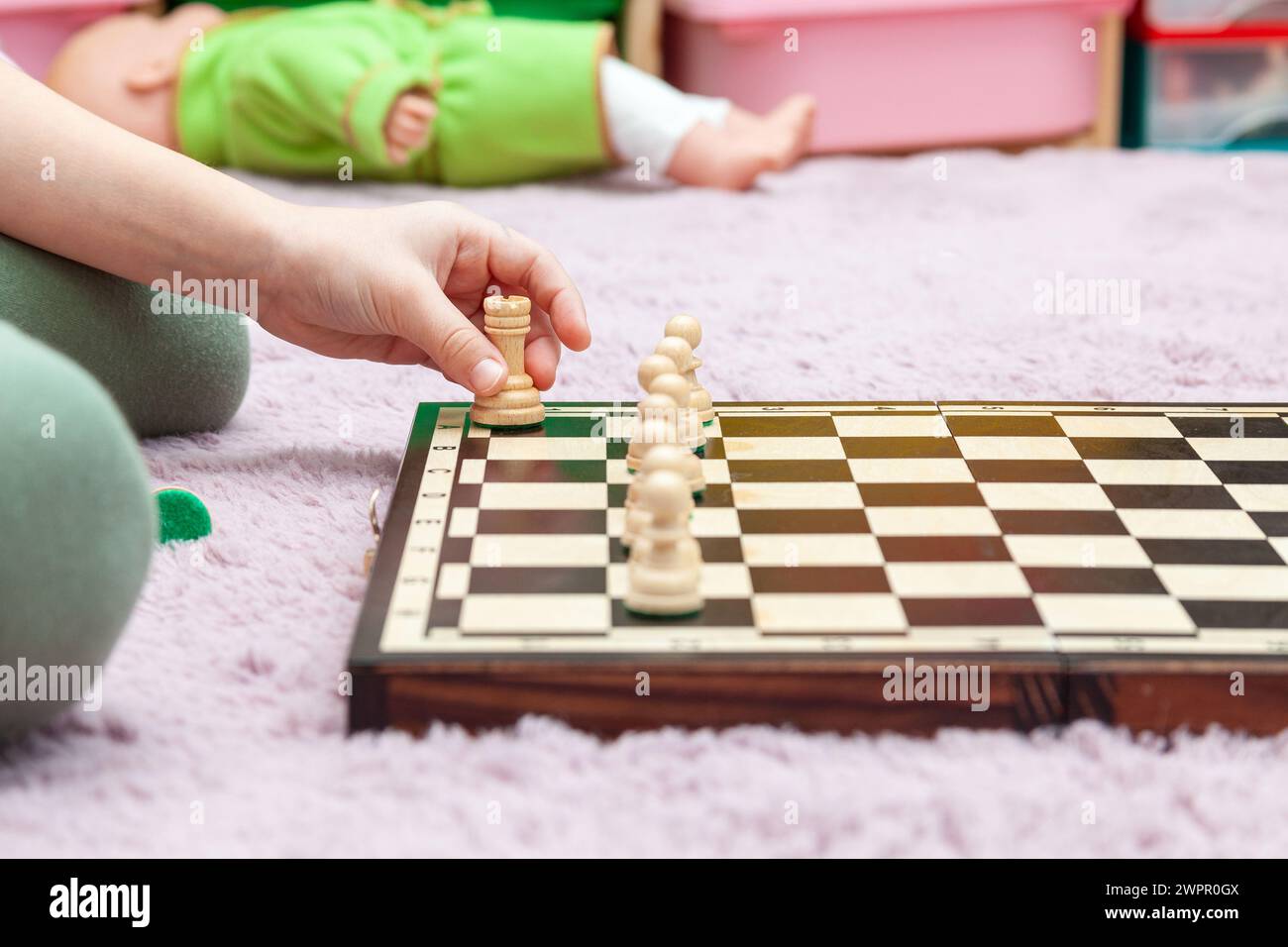 Childs hand grasps a pawn on a chessboard set up for a game, young ...