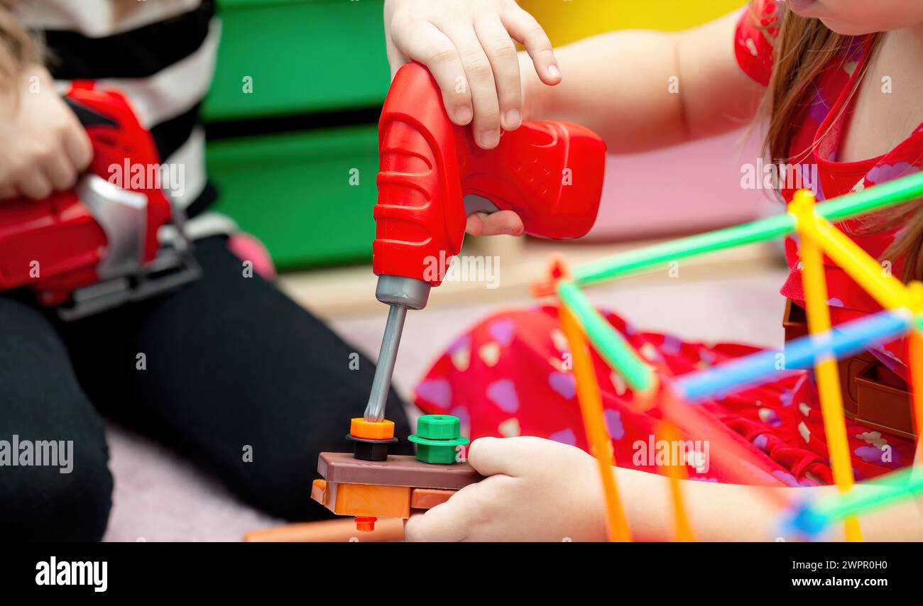 Two children girls assembling a colorful structure using plastic ...