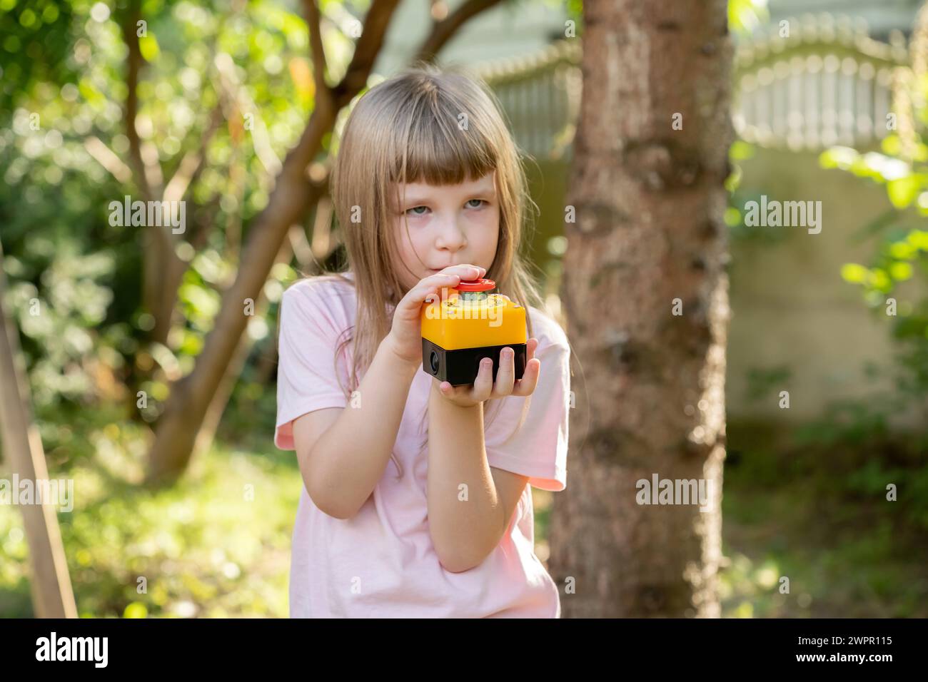 A young girl, child is pressing a large red emergency stop button on a ...
