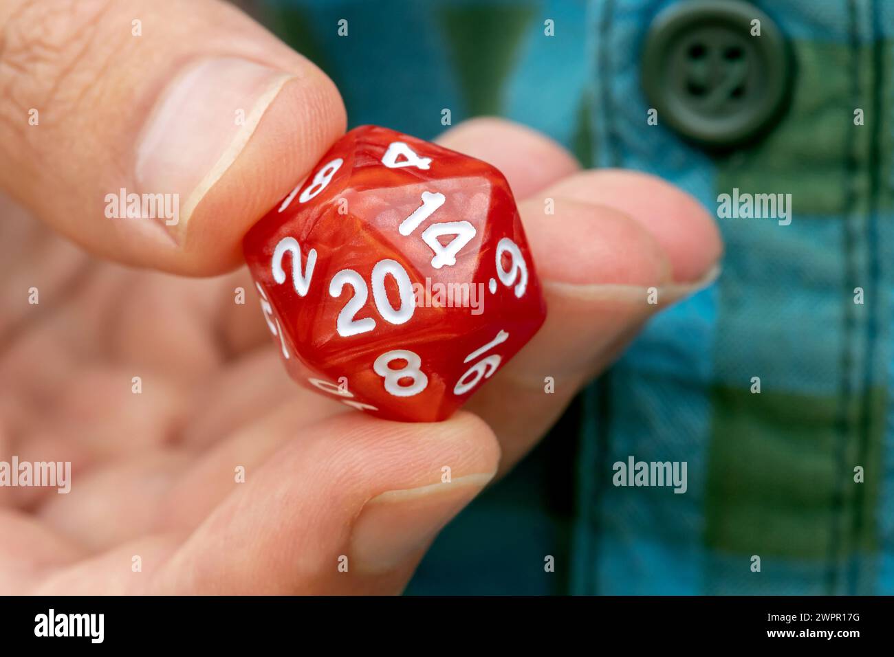 Hand holding a 20-sided d20 dice for RPG gaming, fingers closeup detail ...