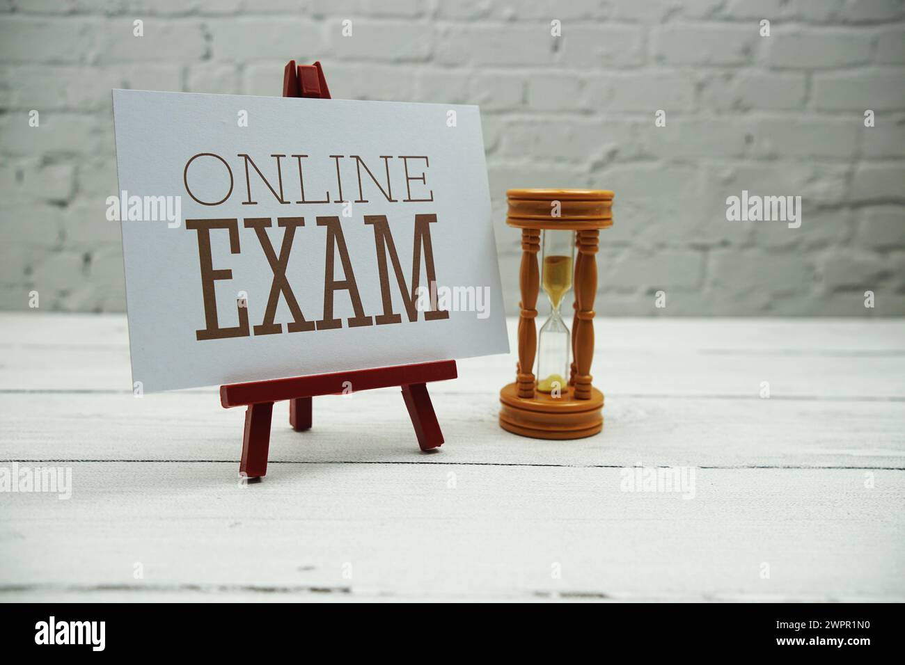 Online Exam text and sandglass on white brick wall and wooden ...