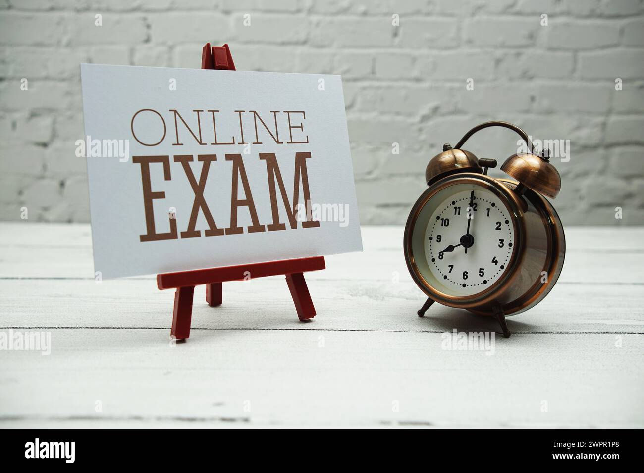 Online Exam text and alarm clock on white brick wall and wooden ...