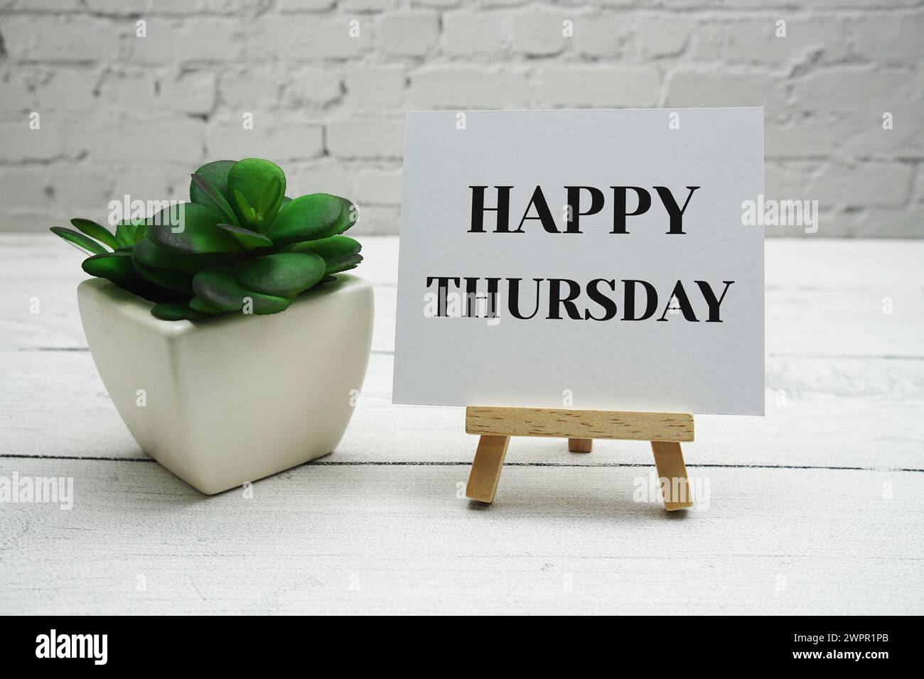 Happy Thursday text on wooden easel standing on white brick wall and ...