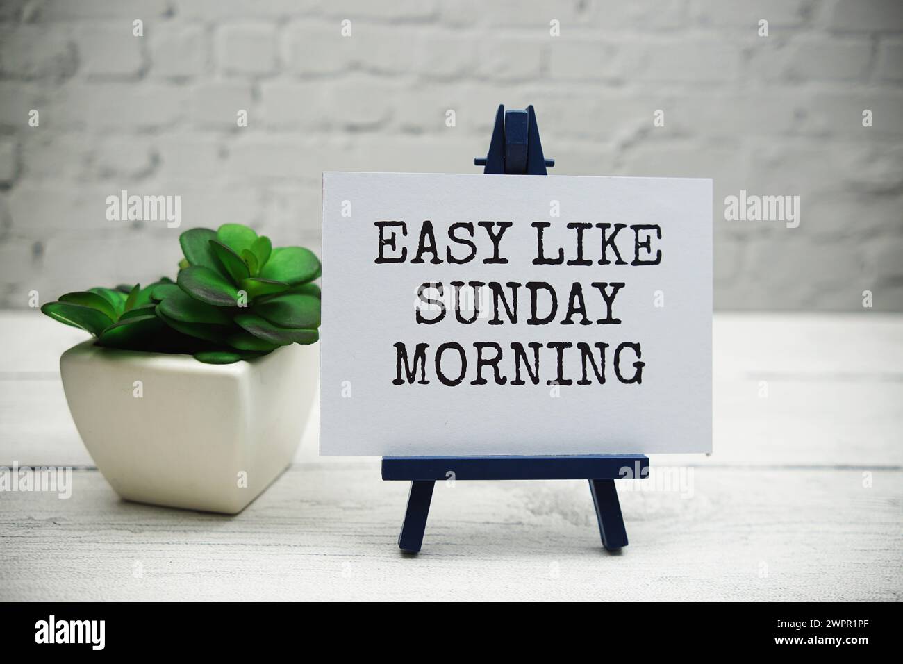 Easy Like Sunday Morning text on white brick wall and wooden background ...