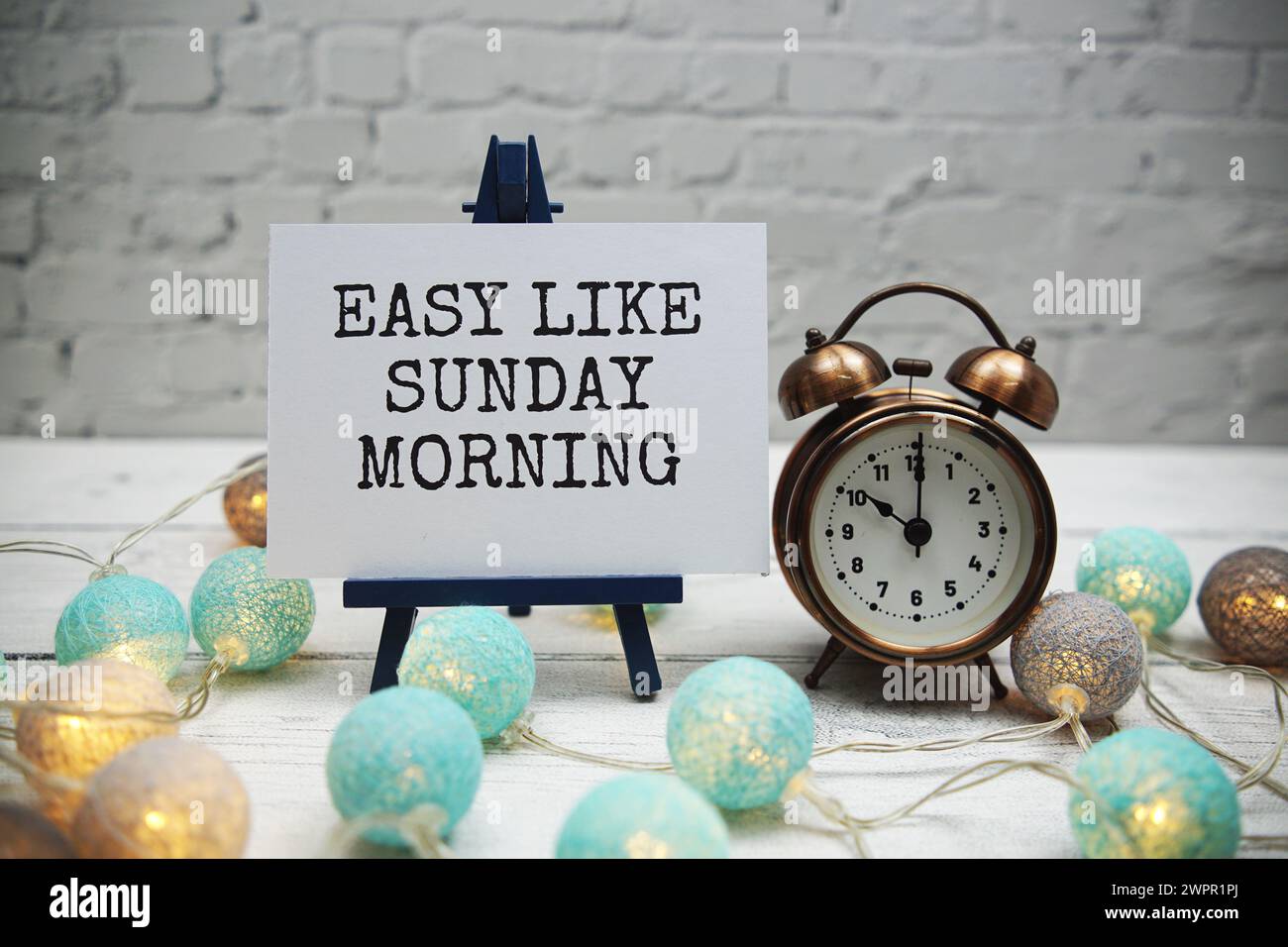 Easy Like Sunday Morning text and alarm clock on white brick wall and ...