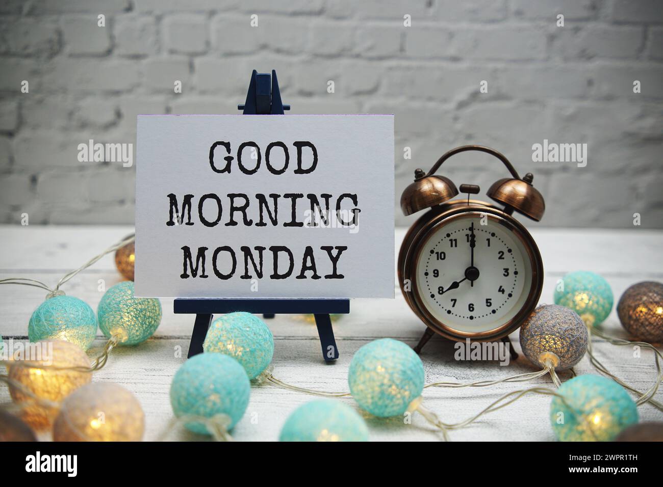 Good Morning Monday text and alarm clock on white brick wall and wooden ...