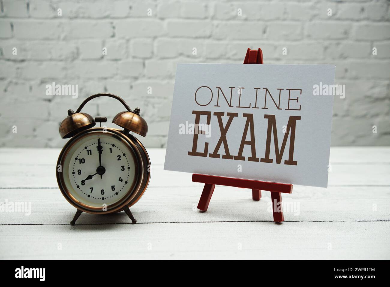 Online Exam text and alarm clock on white brick wall and wooden ...