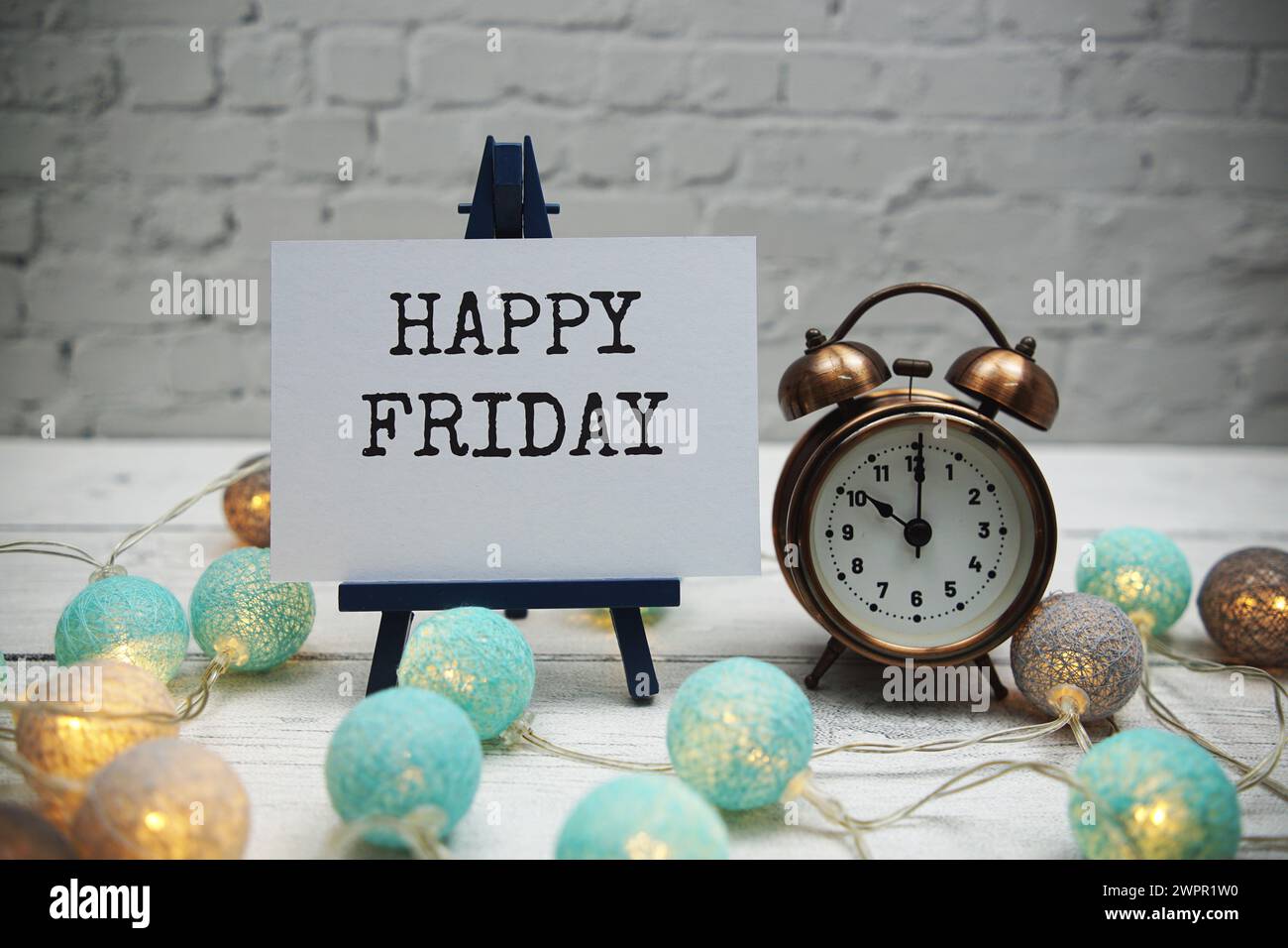 Happy Friday text and alarm clock on white brick wall and wooden ...