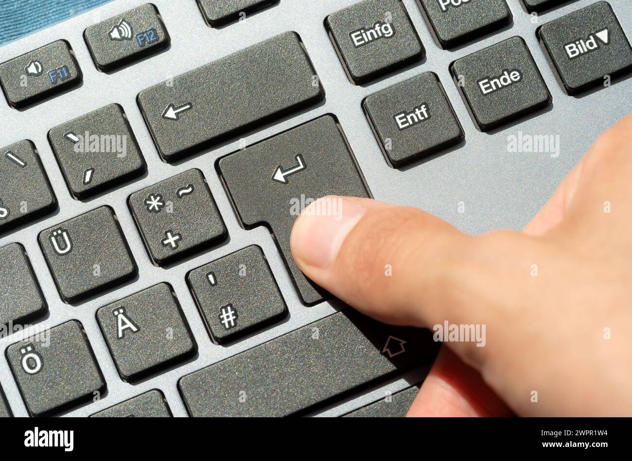 Finger pressing the enter key on a sleek, modern design keyboard ...