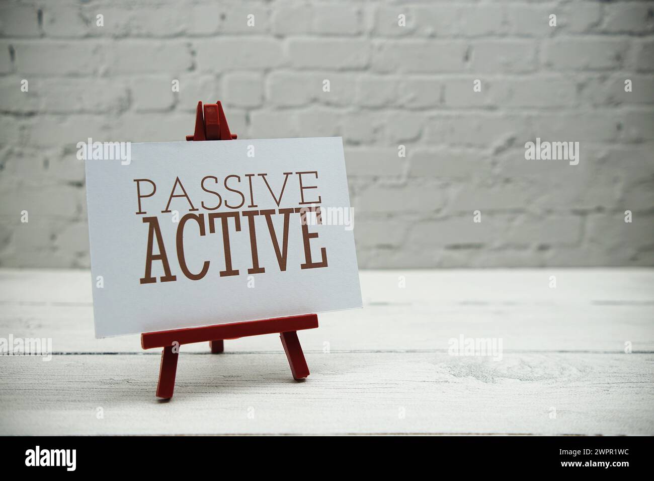 Passive Active text on white brick wall and wooden background Stock ...