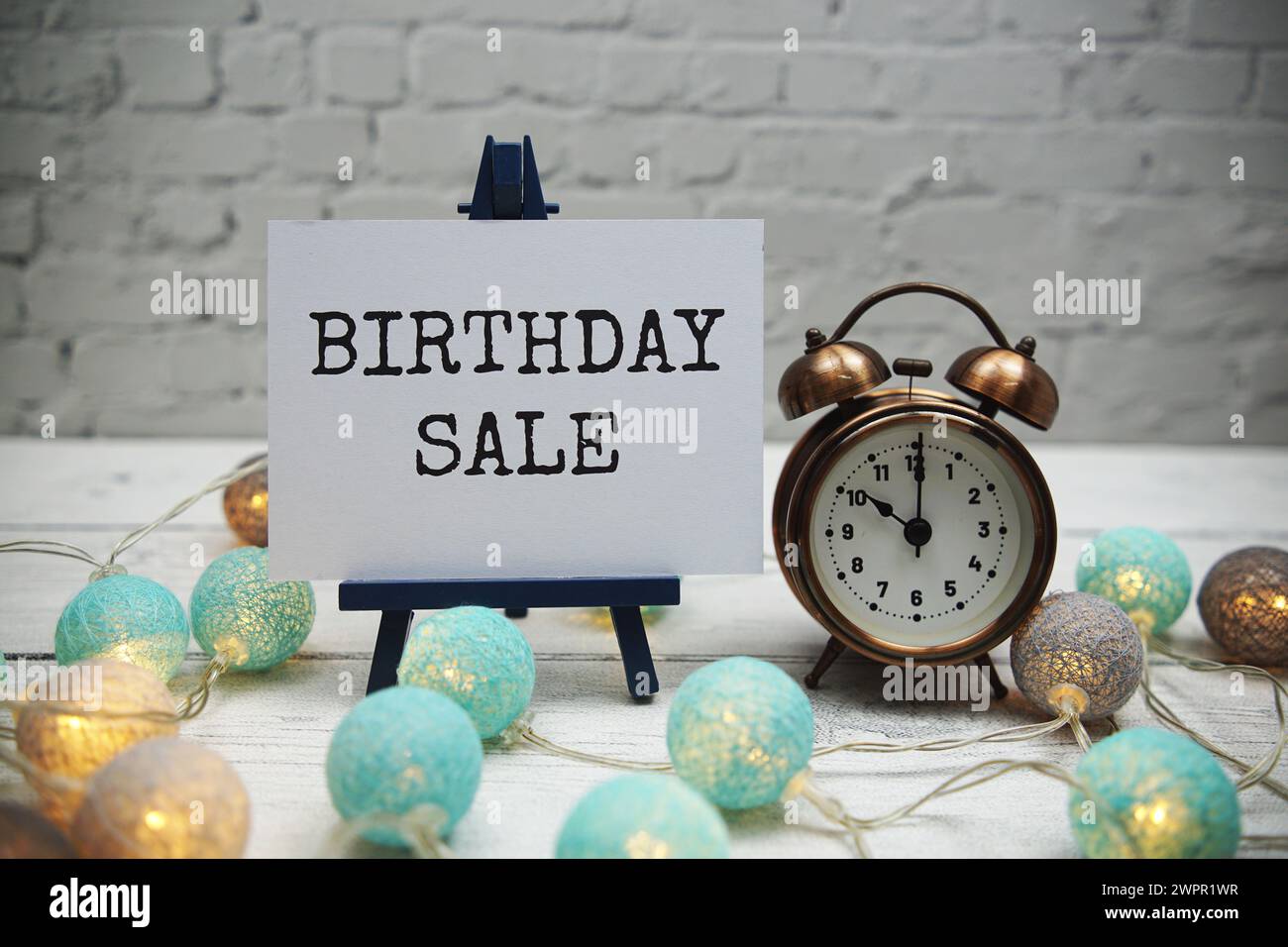 Birthday Sale text and alarm clock on white brick wall and wooden ...