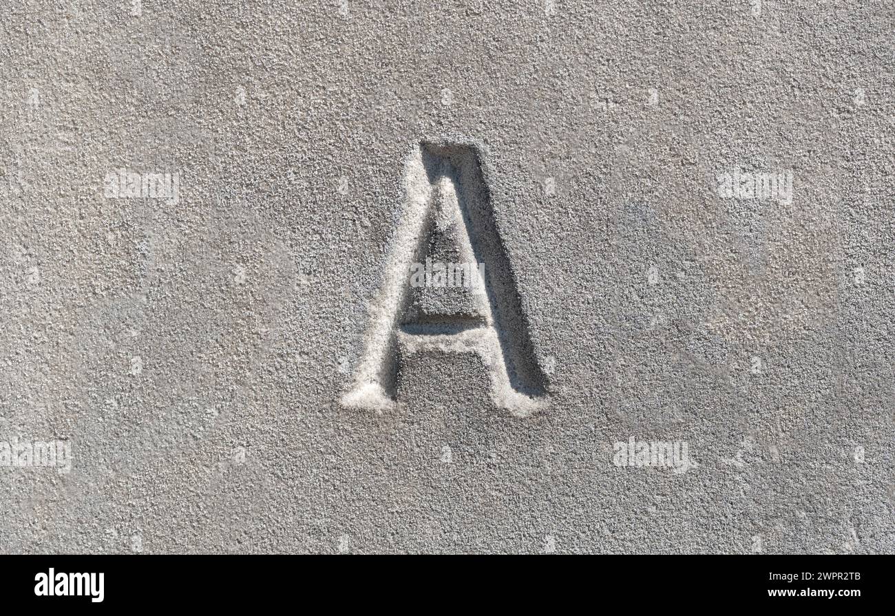 Close-up view of a single one letter A carved into a smooth gray stone ...
