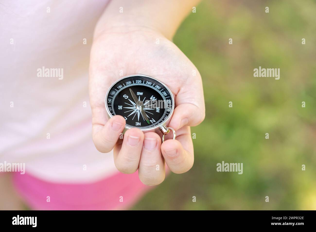 Close-up view of a child holding a black compass in hand blurred ...