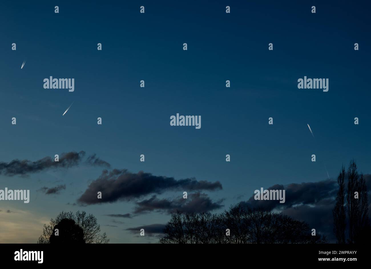 An evening sky in dark blue with a few gray clouds at the bottom and ...