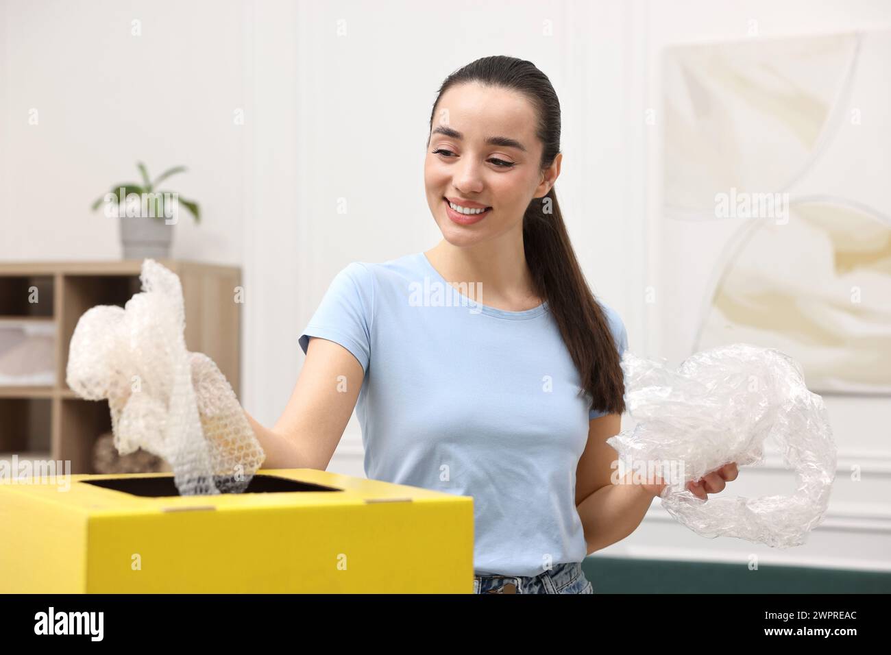 Garbage sorting. Smiling woman throwing plastic package into cardboard ...