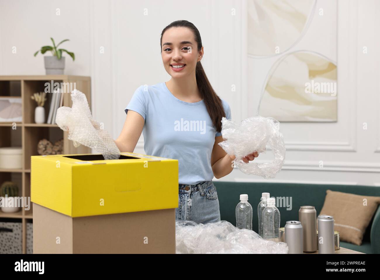 Garbage sorting. Smiling woman throwing plastic package into cardboard ...