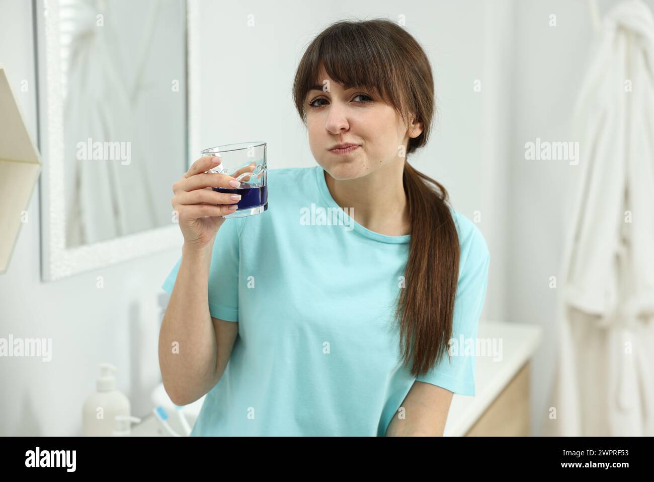 Young woman using mouthwash in bathroom. Oral hygiene Stock Photo - Alamy