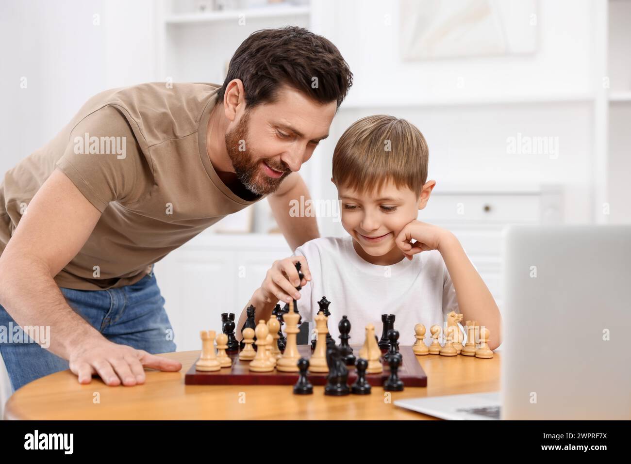 Father teaching his son to play chess following online lesson at home ...
