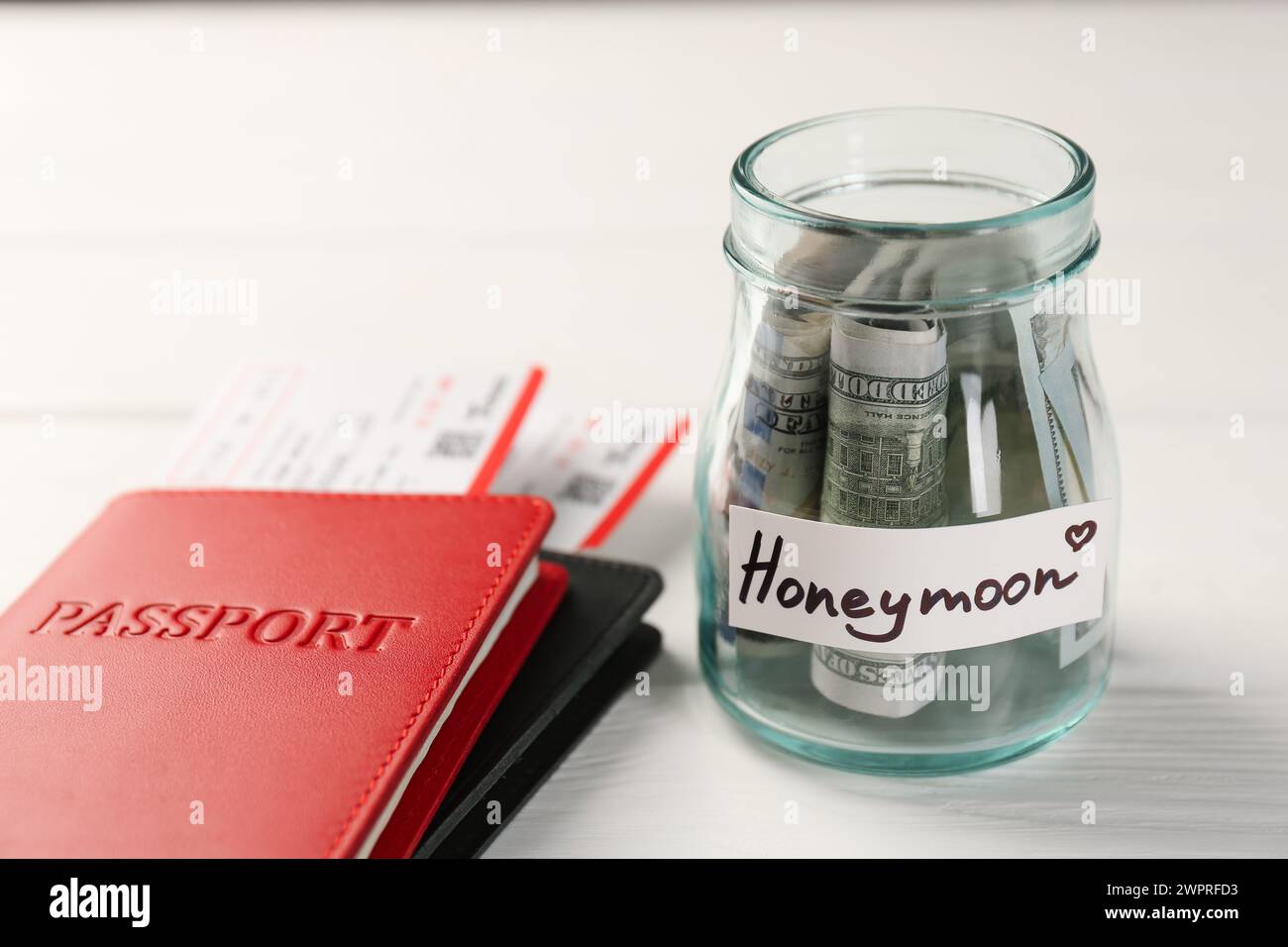 Glass jar with word Honeymoon, dollar banknotes, passports and plane ...