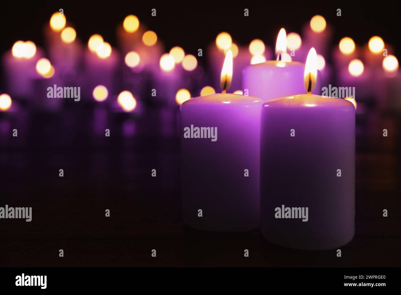 Burning violet candles in darkness, space for text. Funeral attributes ...