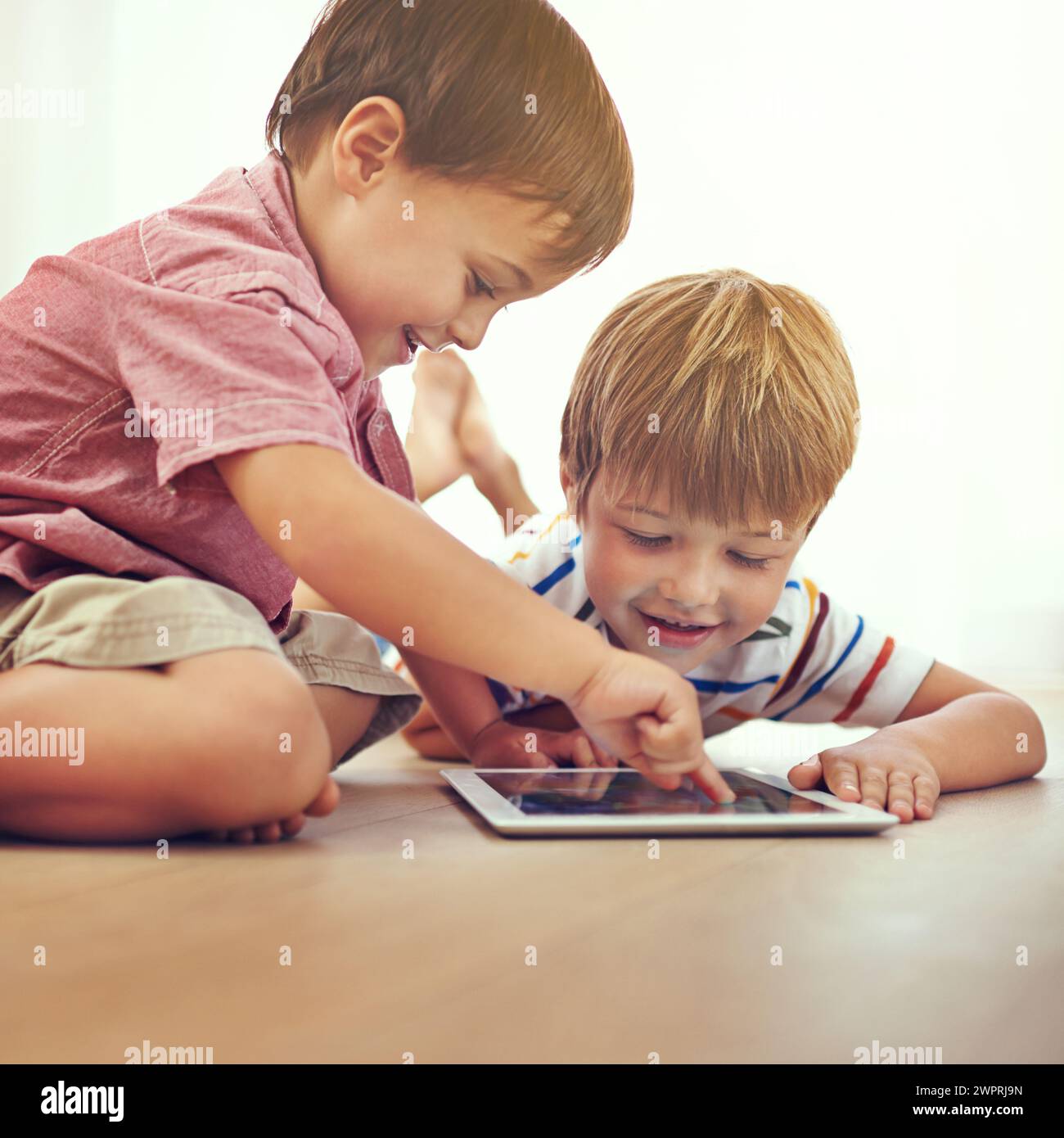 Children, siblings and tablet on a floor with cartoon, gaming or streaming movie at home ...