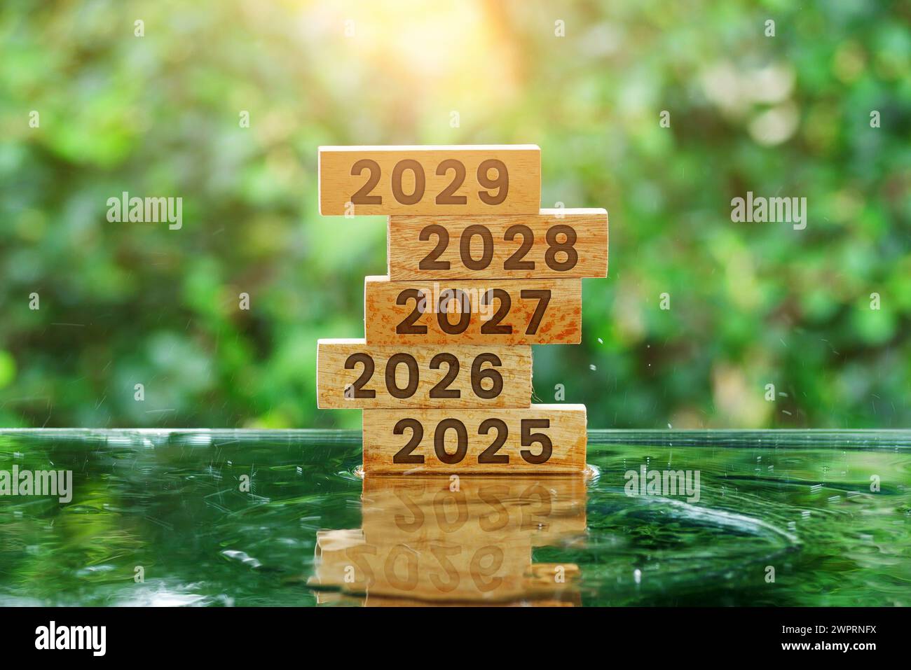 Stack of wooden blocks with years 2025 to 2029 on water reflection ...