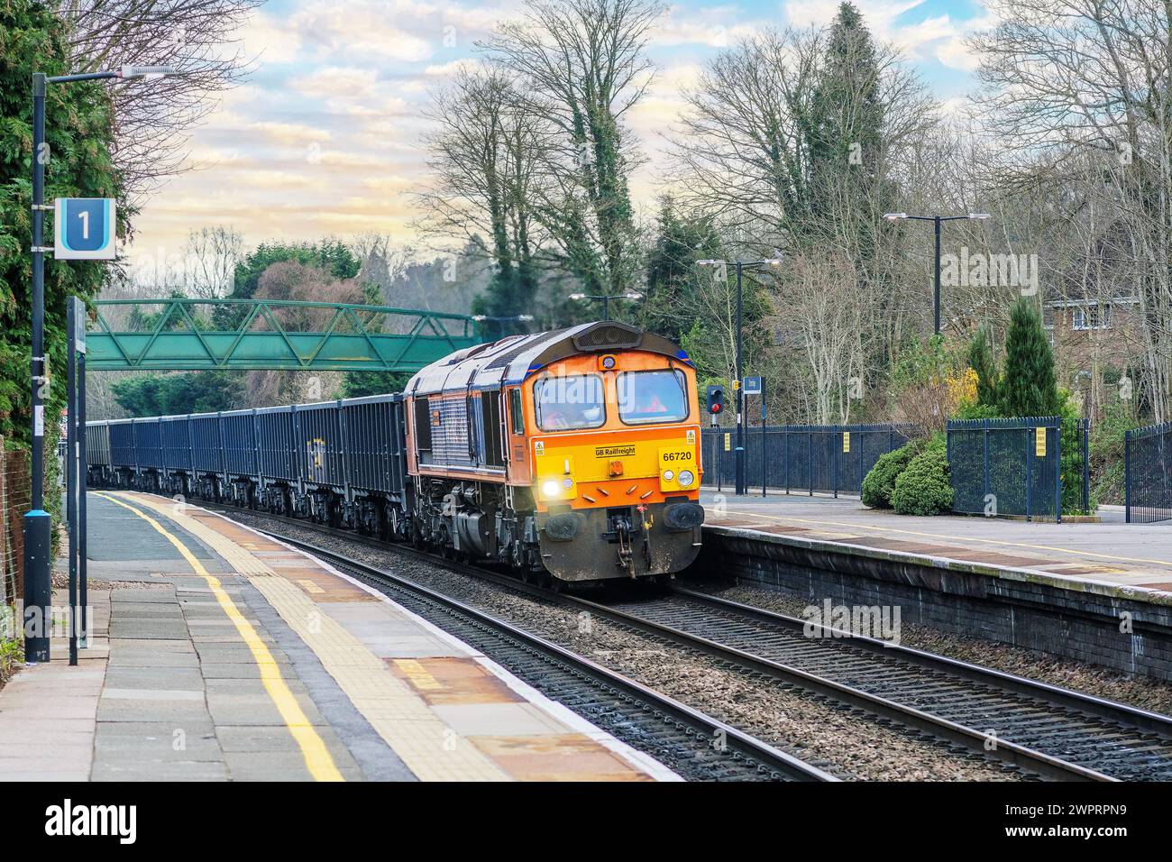 diesel powered freight train passes through suburban railway station ...