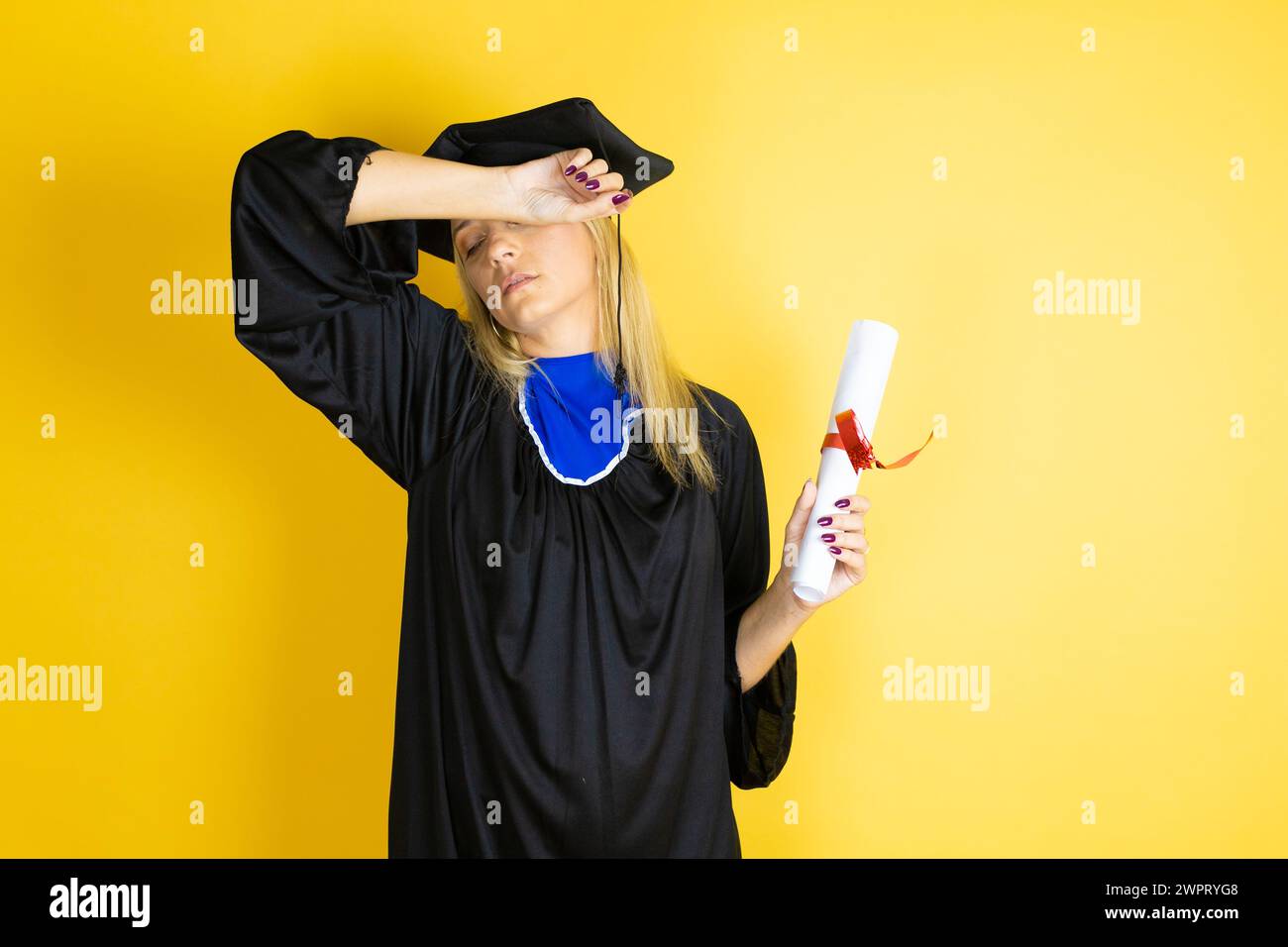 Beautiful blonde young woman wearing graduation cap and ceremony robe ...