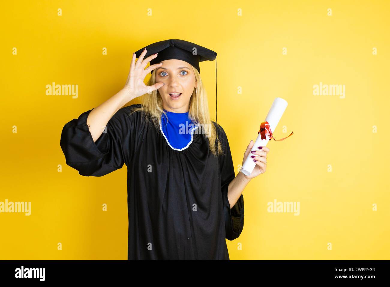 Beautiful blonde young woman wearing graduation cap and ceremony robe ...