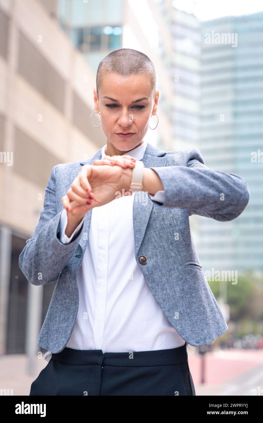 Vertical portrait of a serious business woman looking at the time on ...