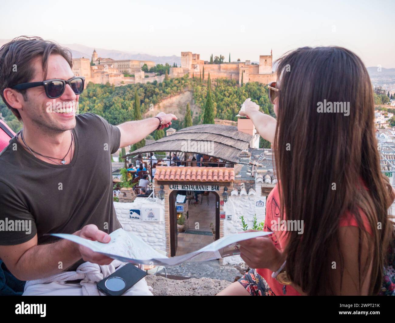 couple of handsome tourists in love with sunglasses and map point to ...