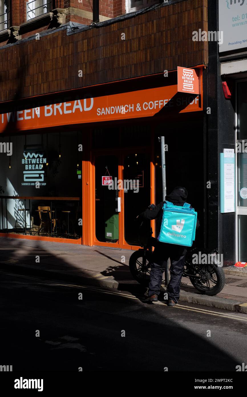 Deliveroo courier rider collecting a food order from a cafe restaurant ...
