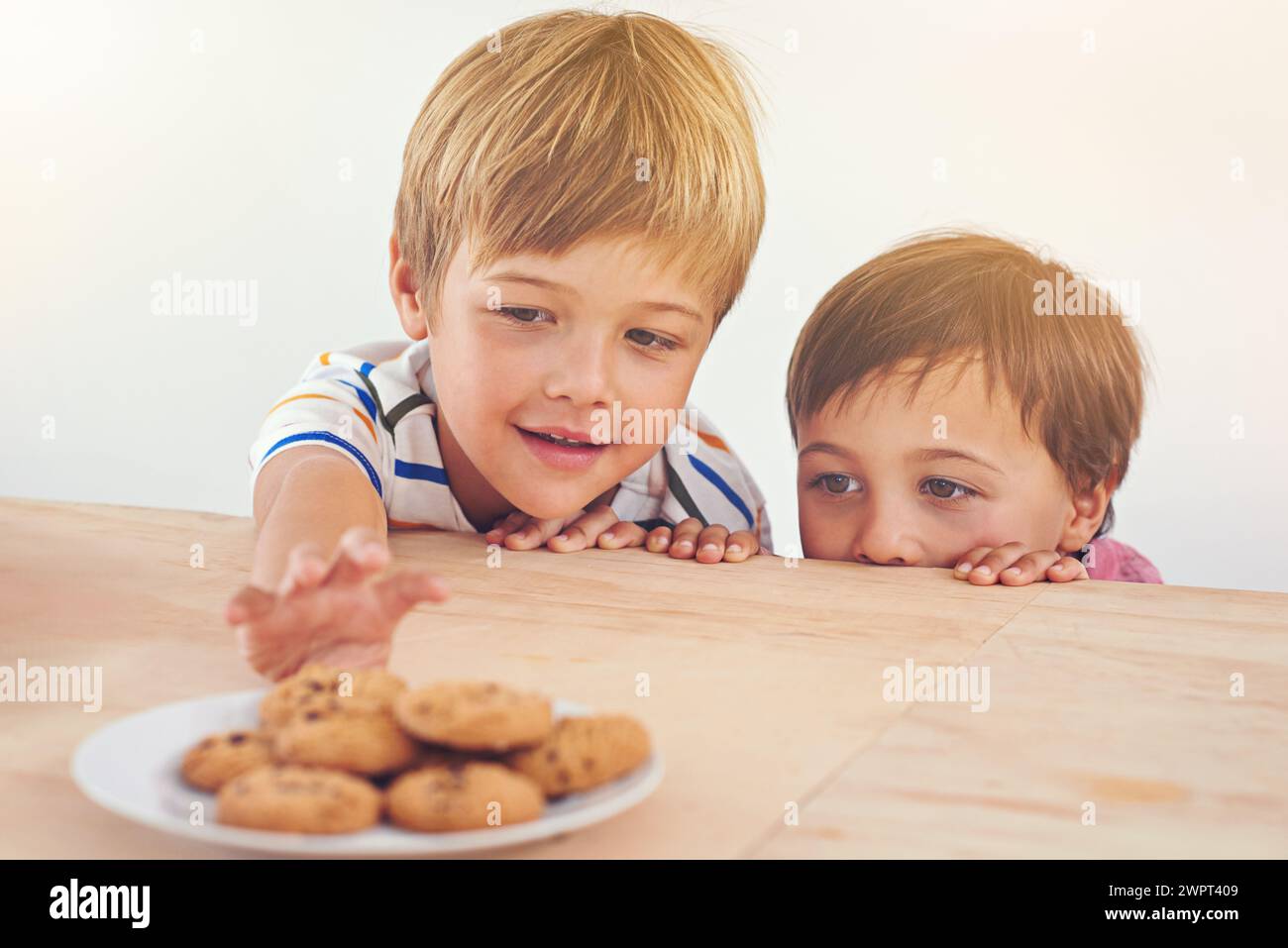 Kids, boys and smile for cookies in home with stealing, peeking and ...