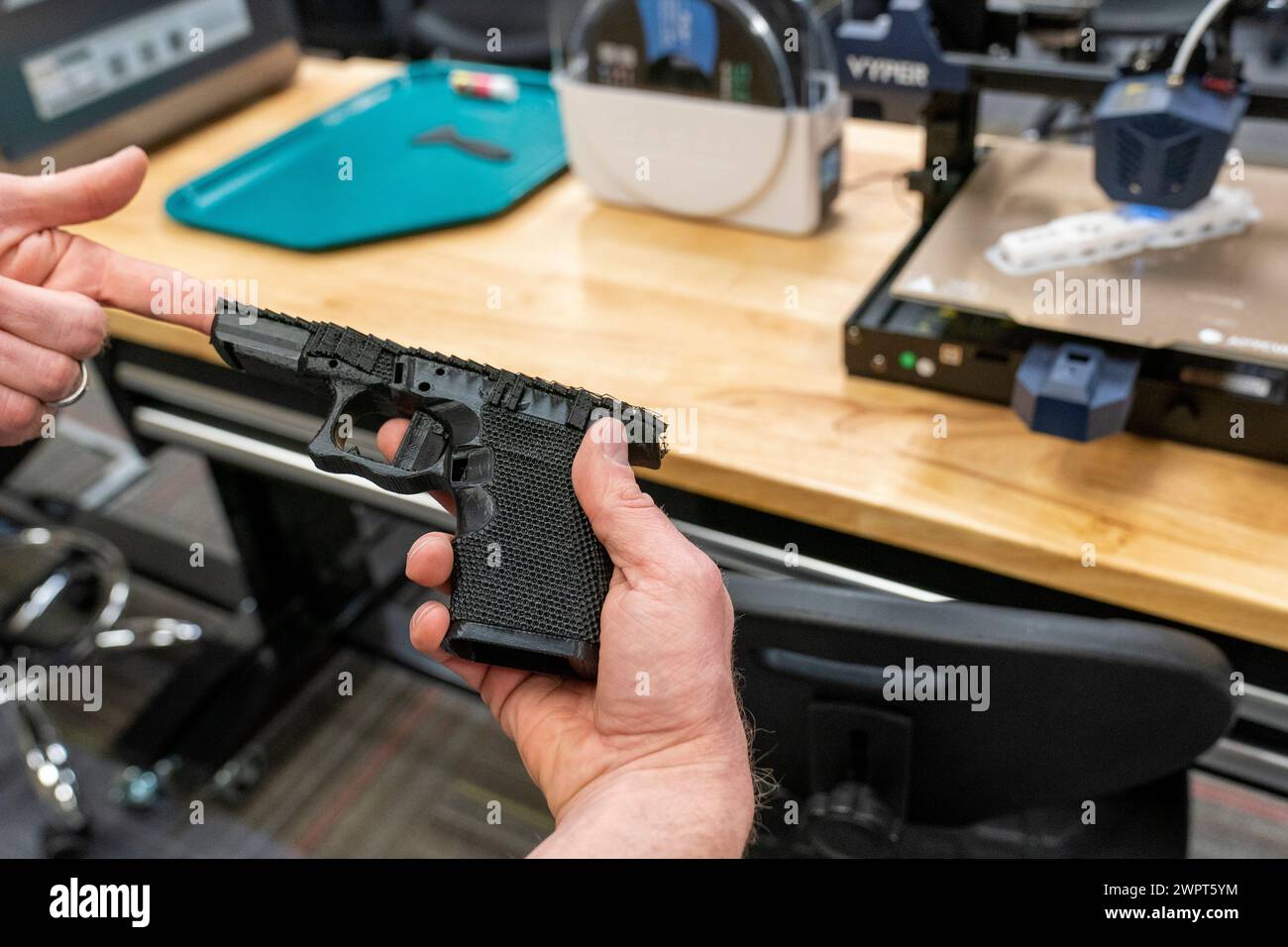 A handgun frame that has been printed on a 3D printer is held for a ...