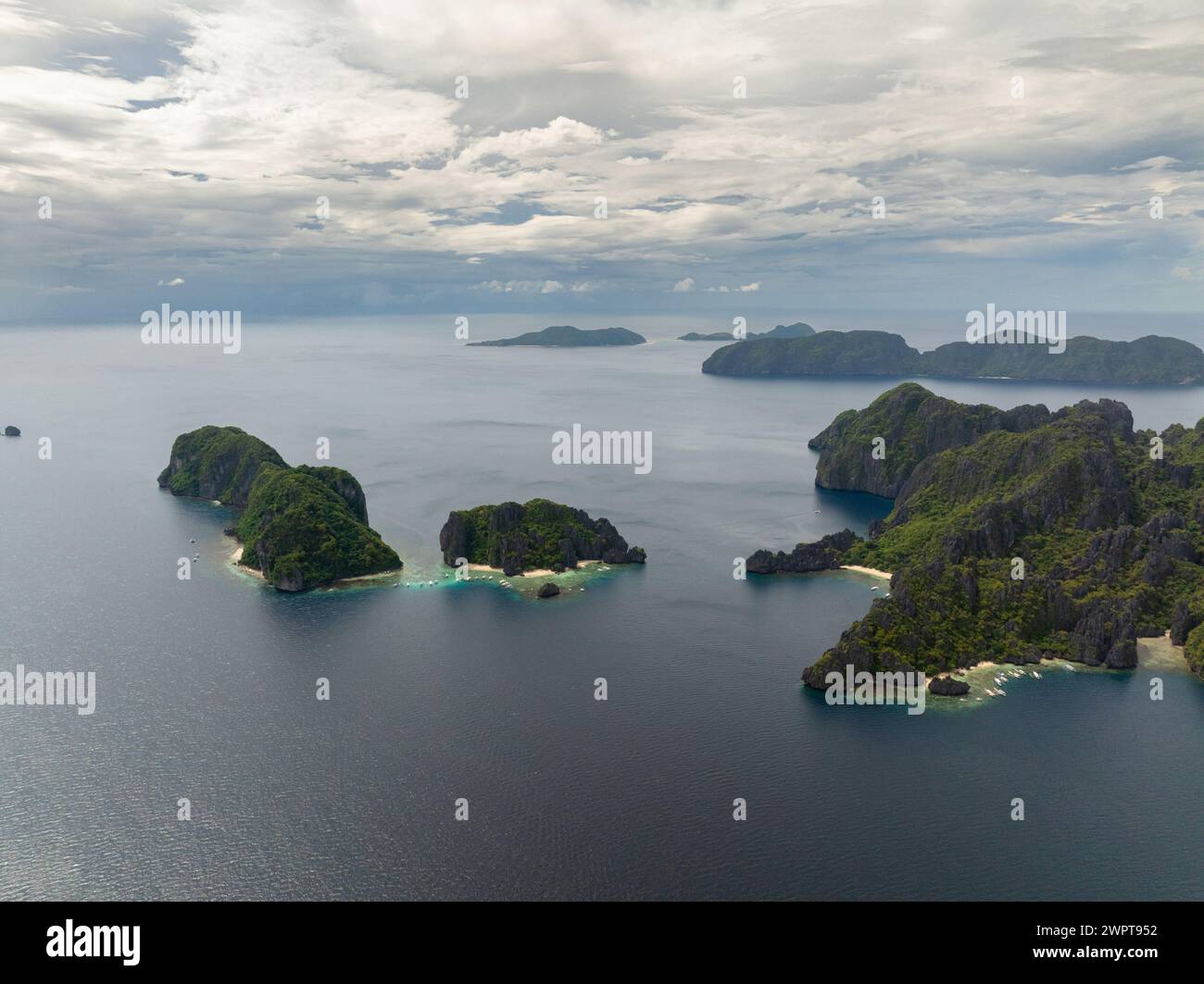 Twin Rocks with white sand and boats surrounded by blue sea. El Nido ...