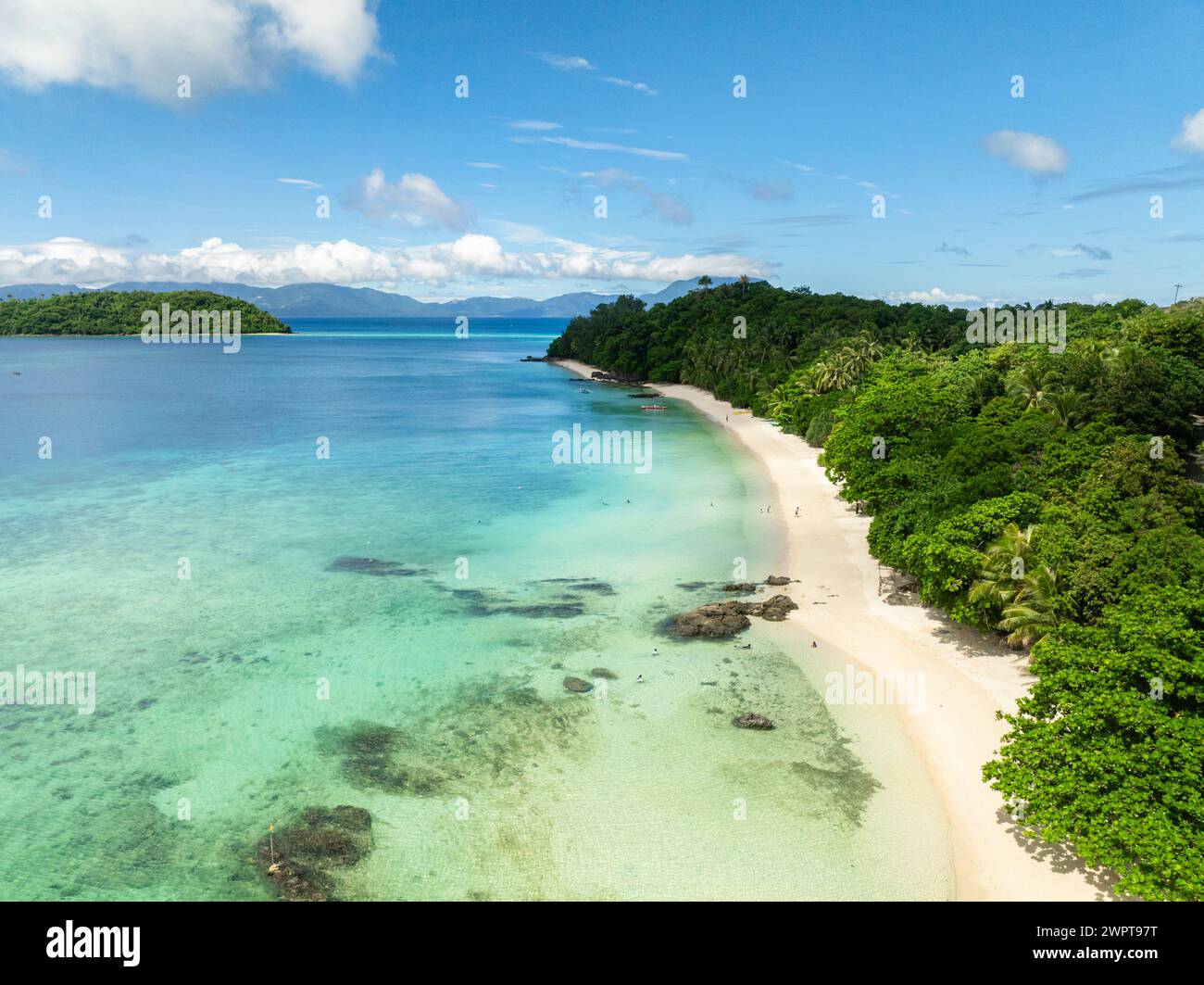 Flying over the Tiamban Beach with clear ocean waves on white sandy ...