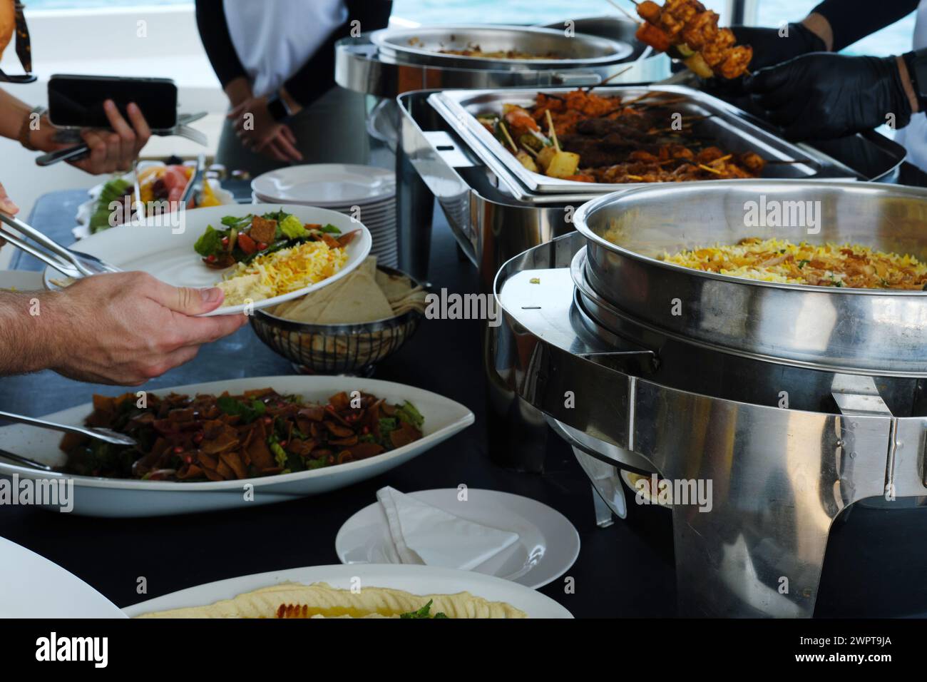 A buffet on a yacht in Dubai with a service attendant carefully plating ...