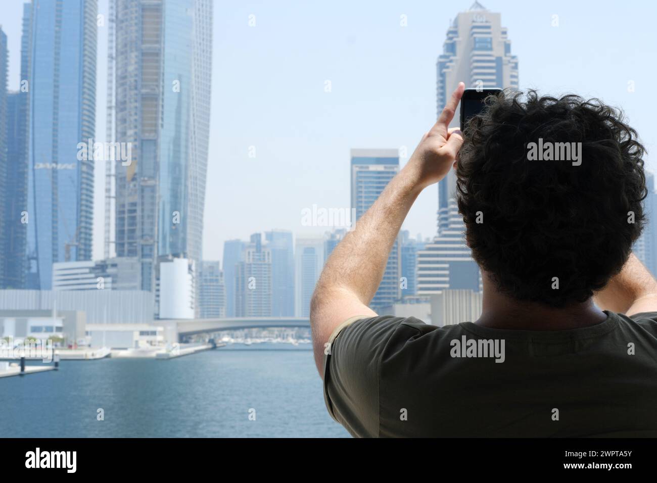 A young man takes pictures of the Dubai cityscape with his mobile phone ...