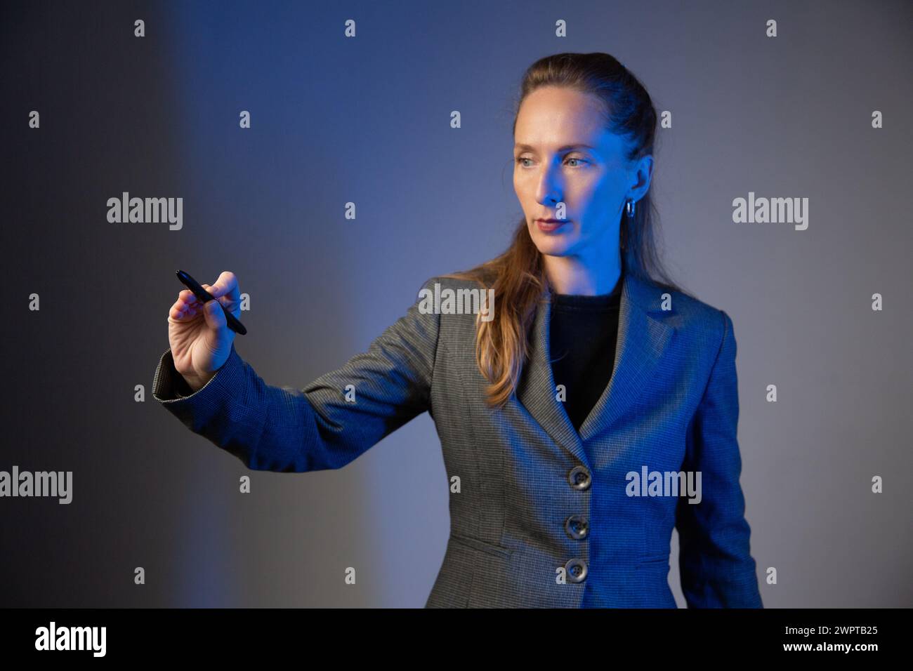 Business woman holding a light pencil in her right hand on a gray ...