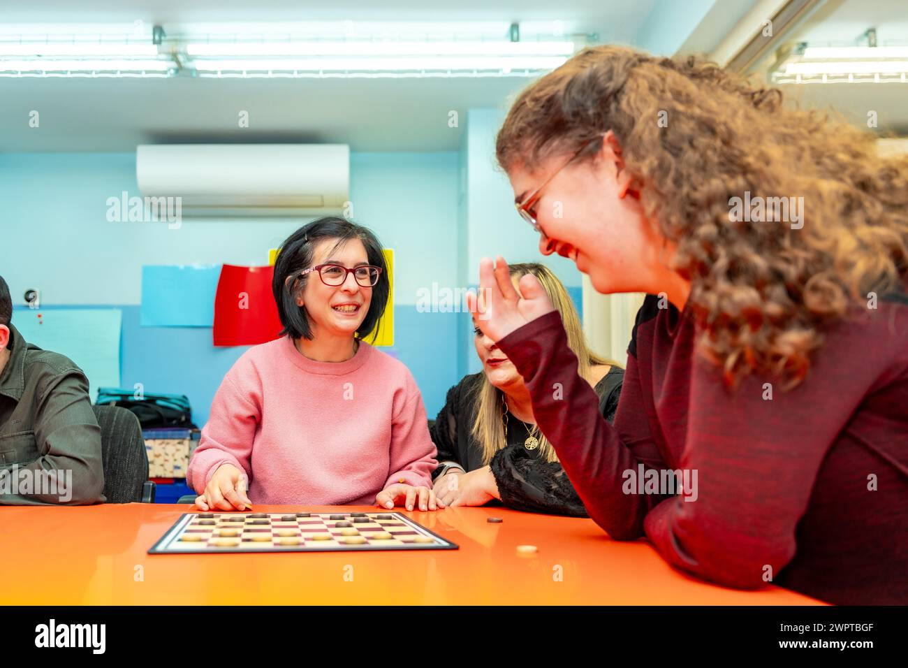 Caregiver and woman with special needs playing with board games on a ...